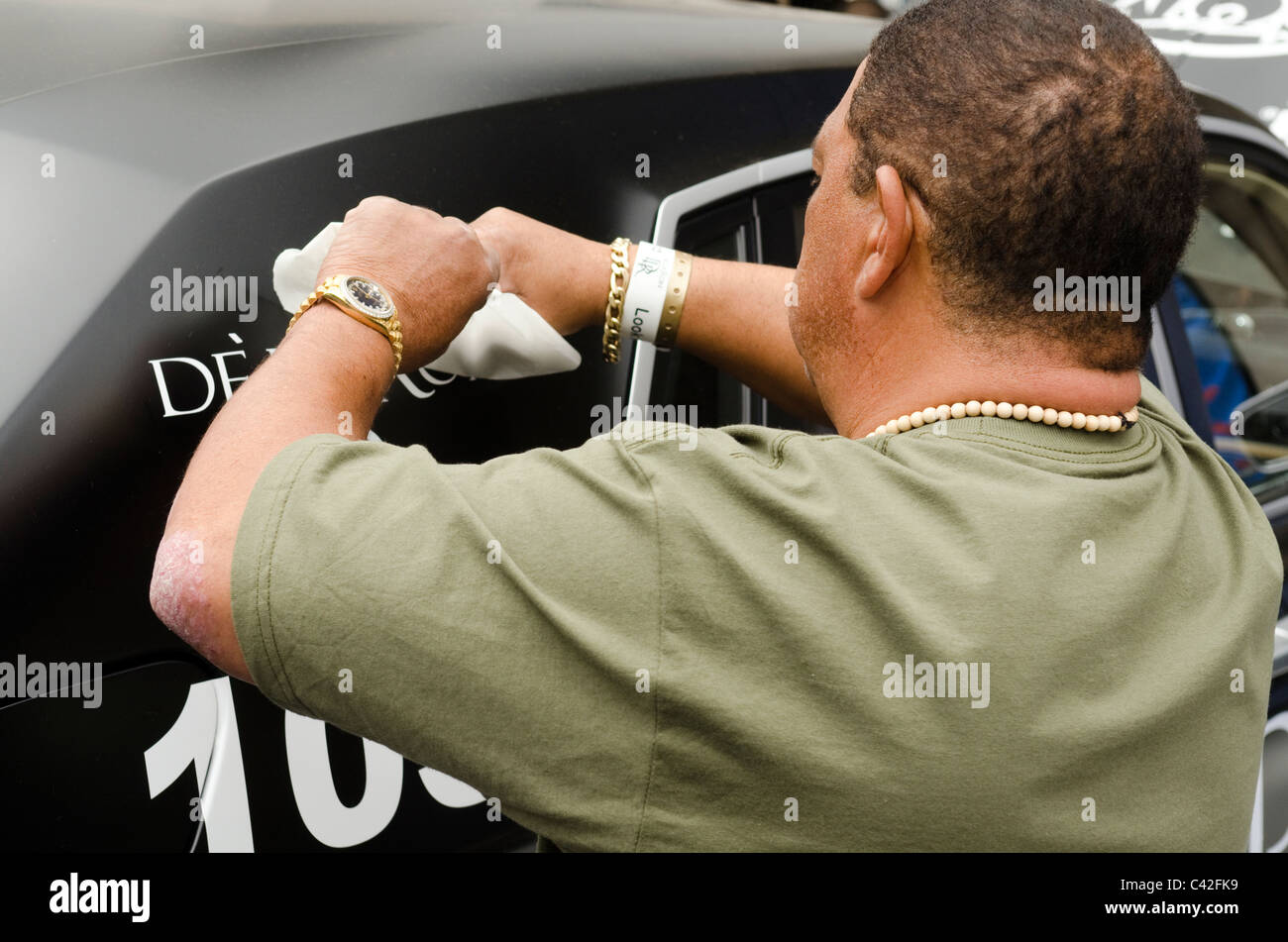 man placing a decal on a car at the Gumball rally 3000 Covent Garden ...
