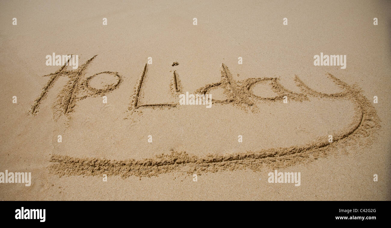 Holiday written in sand Stock Photo - Alamy
