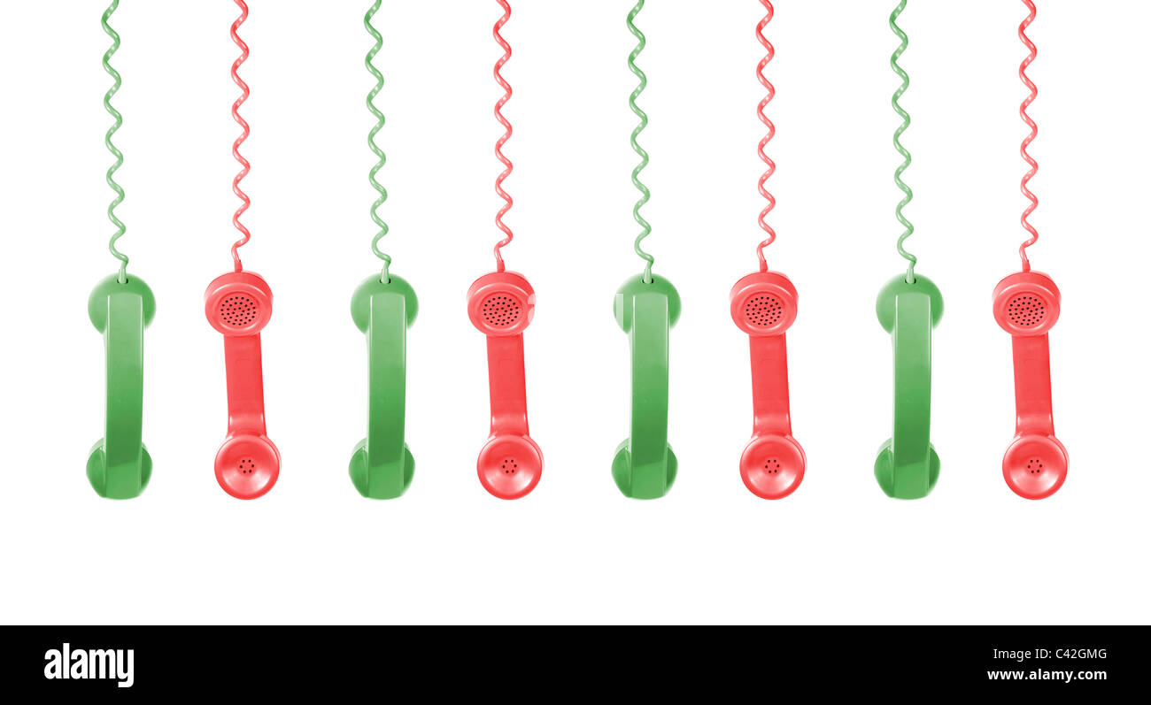 Green and red coloured old phone handsets are hanging on white ...