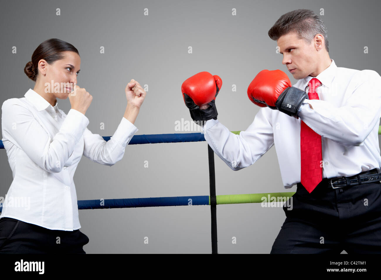 Portrait of aggressive businessman in boxing gloves and serious female ...