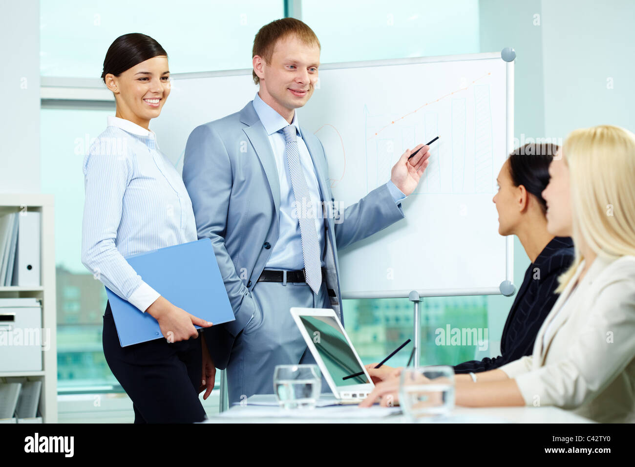A business man explaining something on a whiteboard with pretty woman ...