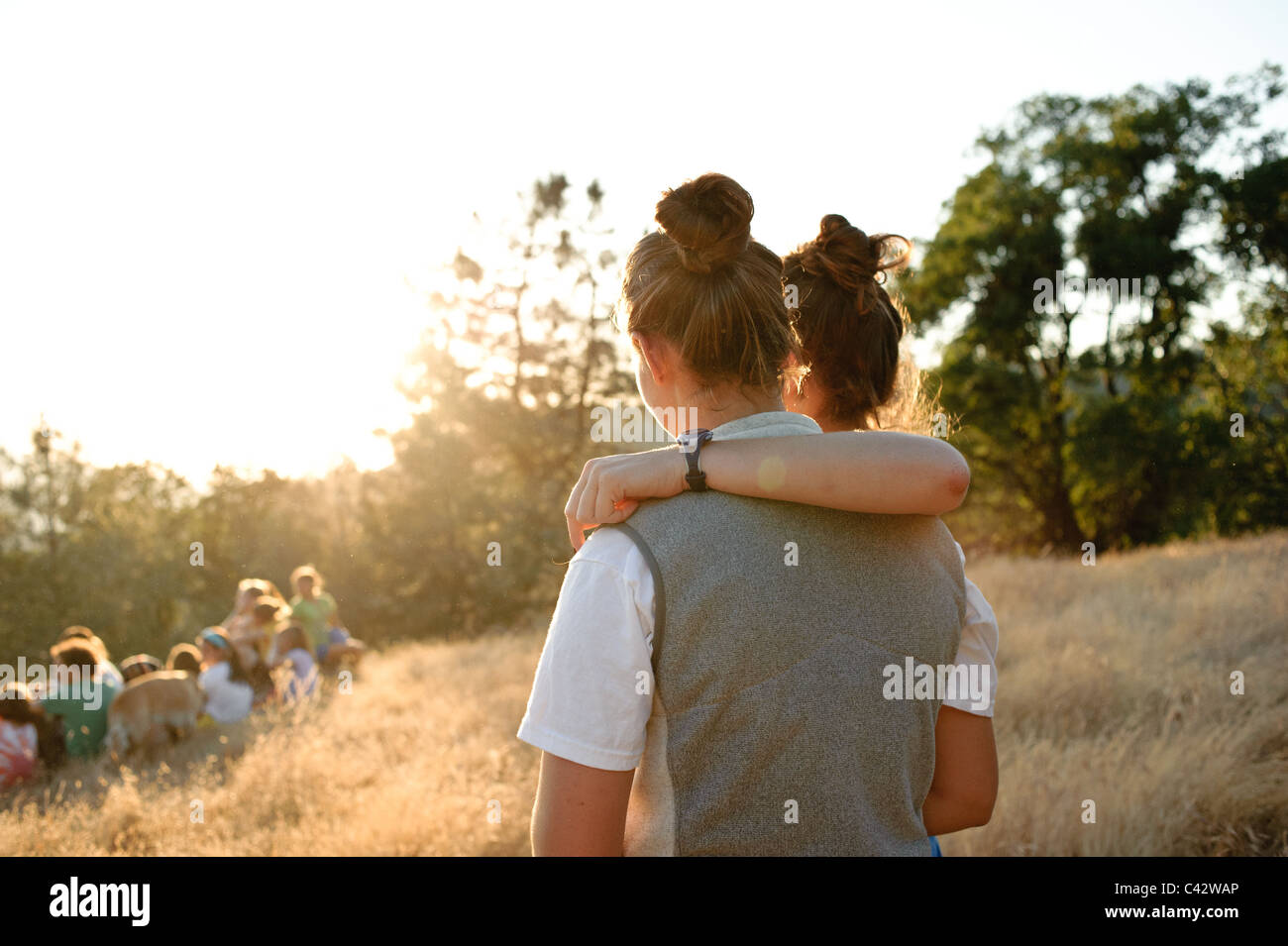 Two teenage girls with arms around eachother at sunset Stock Photo - Alamy