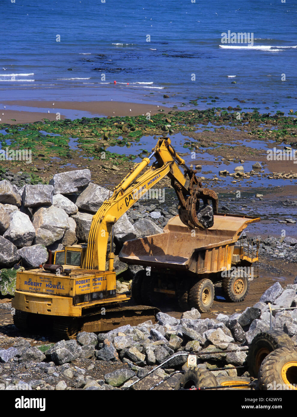 heavy machinery moving giant stone boulders building sea defences at ...