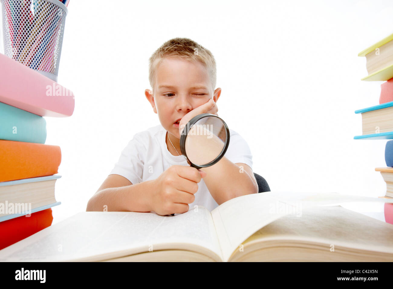 Smart youth reading open book before him with serious facial expression ...