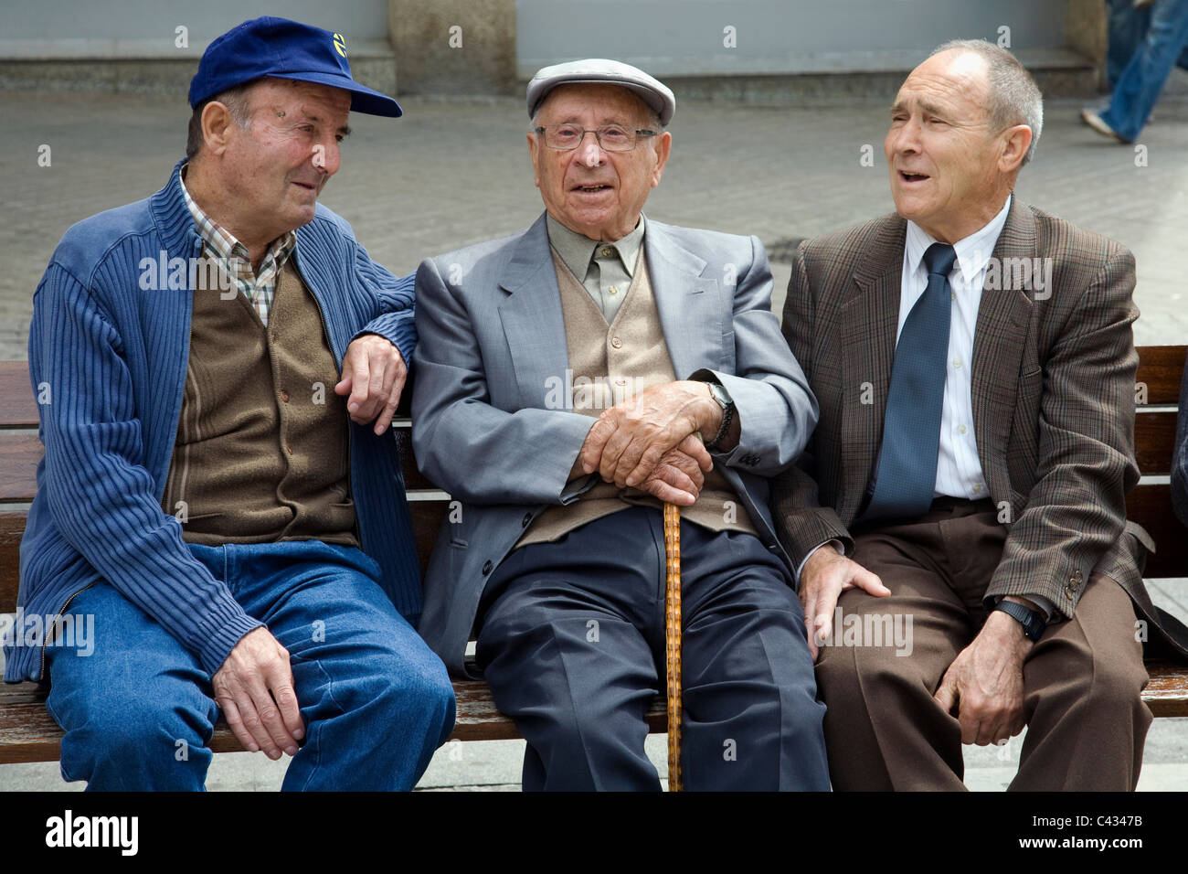 Three Catalan men sat talking on a bench Stock Photo - Alamy
