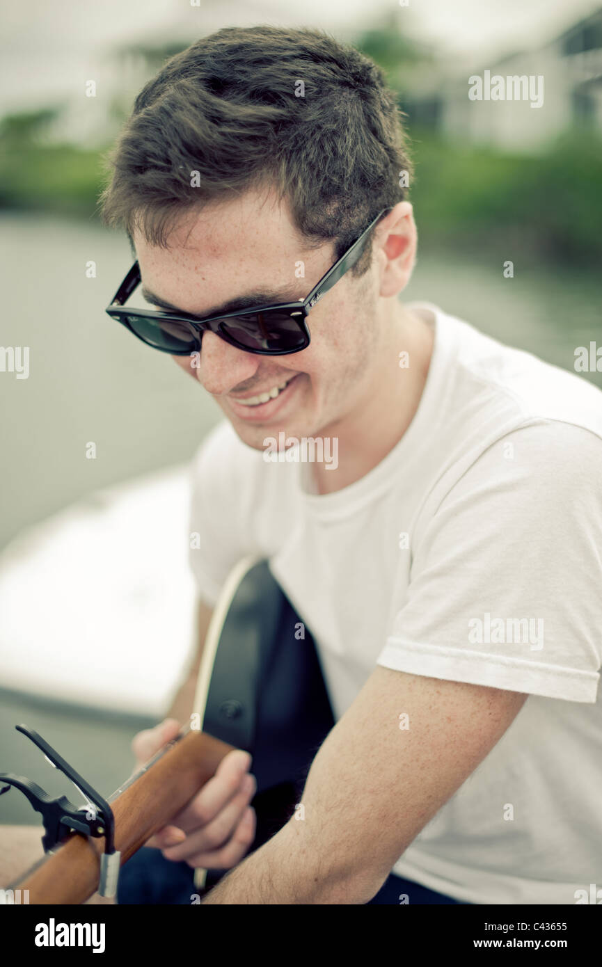 Young adult smiling and playing guitar Stock Photo - Alamy