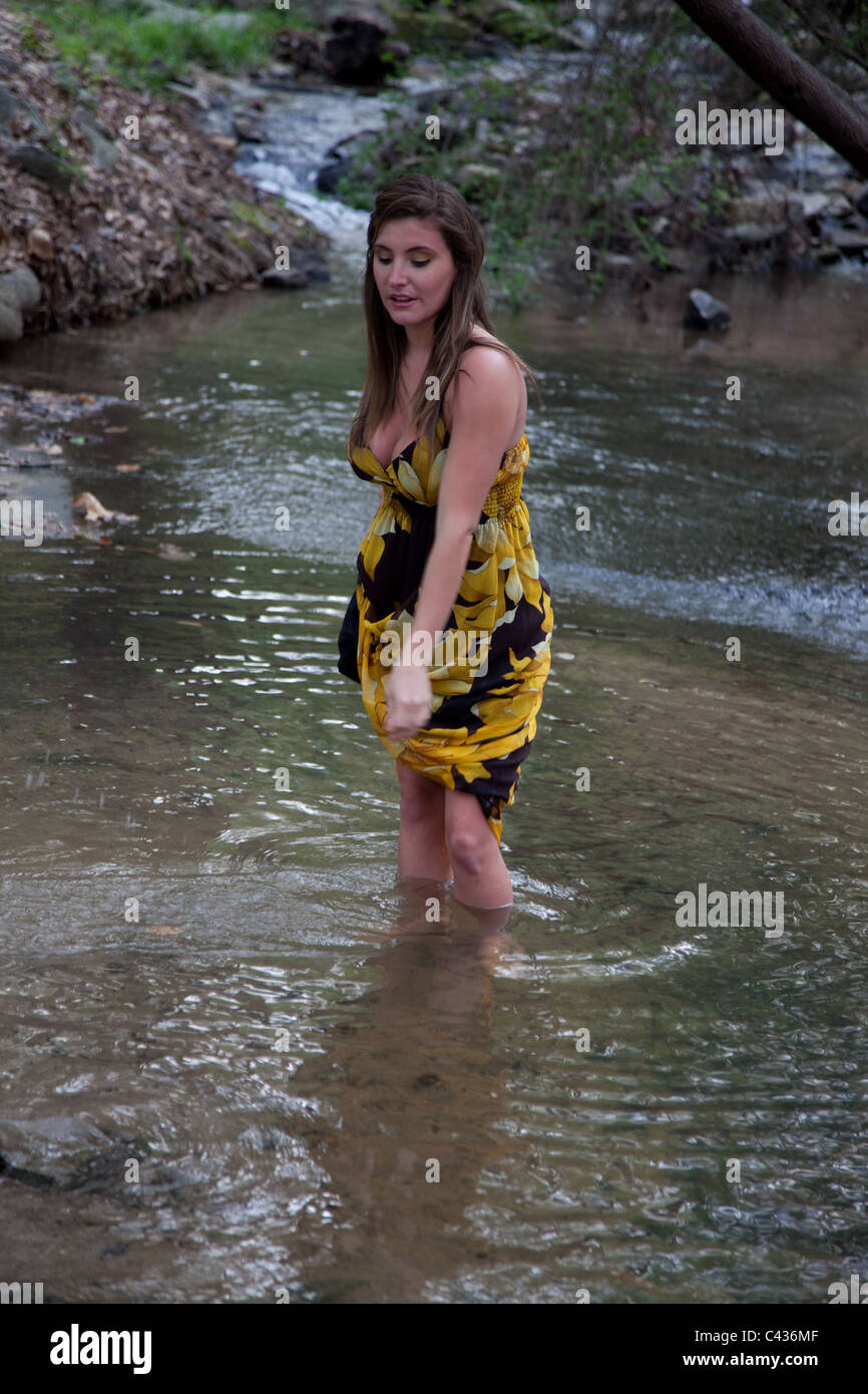 Caucasian woman in yellow dress playing outside in a quiet pool of ...