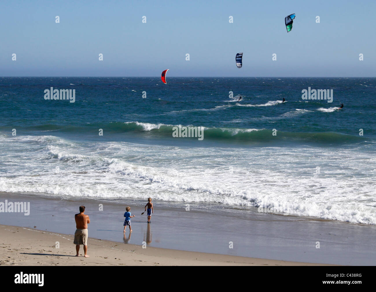 Family on the beach watching kite surfers Stock Photo - Alamy