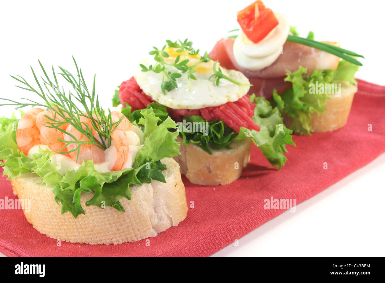 Canape with lettuce, ham, steak tartare, shrimp and quail eggs on a ...