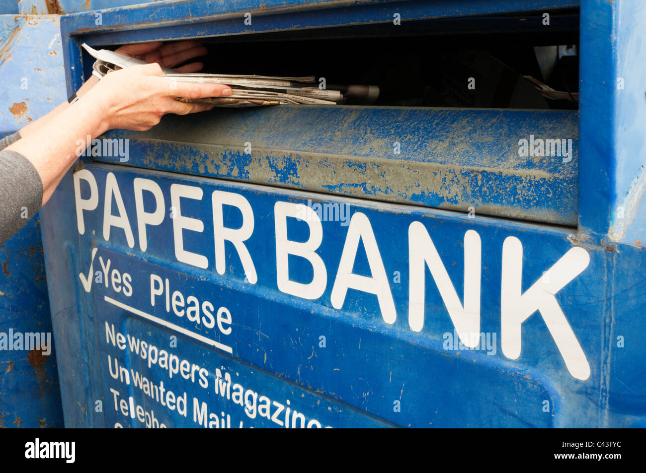 A woman recycling newspapers in a large paper bank Stock Photo - Alamy