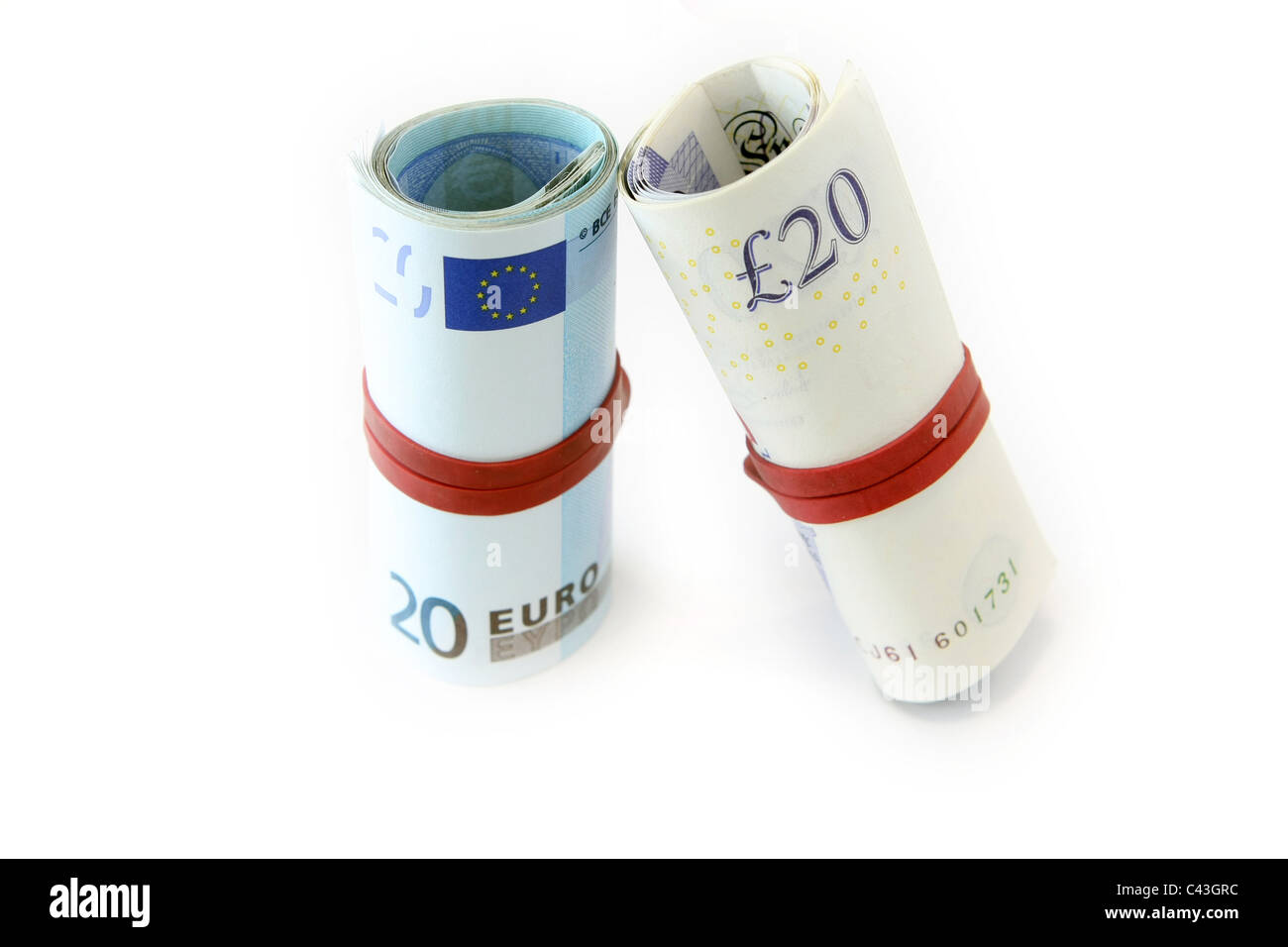 A rolled up bundle of sterling £20 notes leaning against a rolled up ...