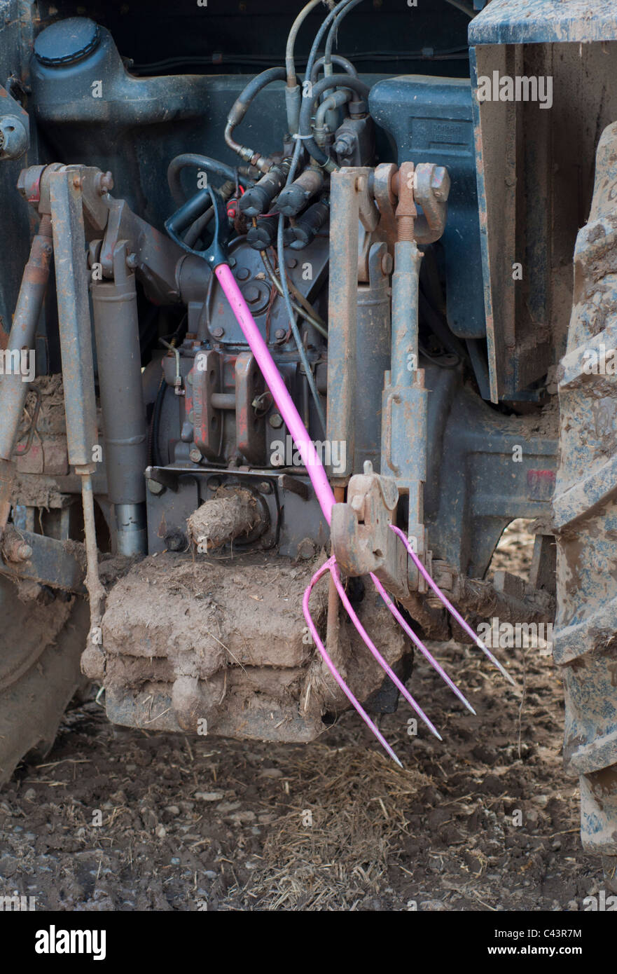A pink pitchfork sits on the back of a Massey Ferguson tractor Stock ...