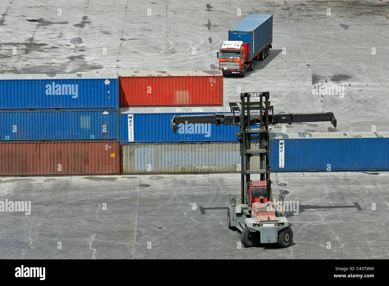 Stacked shipping cargo containers, truck and forklift at shipyard Stock ...