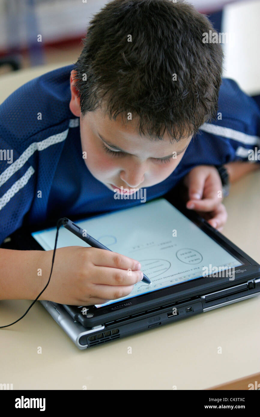 Kid using tablet PC in classroom Stock Photo - Alamy