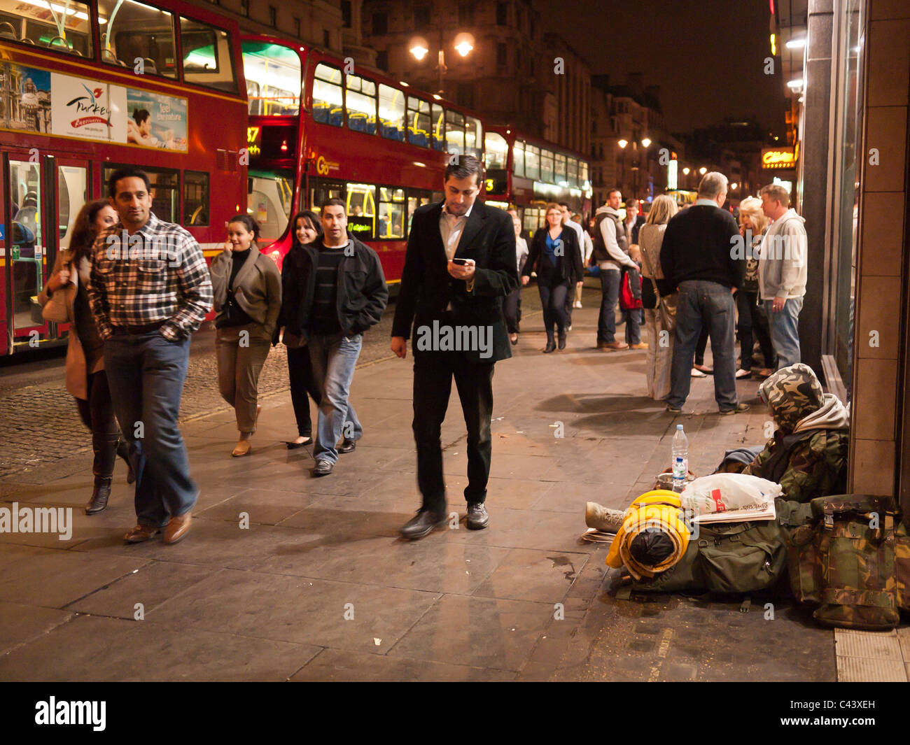 homeless person on the street with sleeping bag as people walk past ...