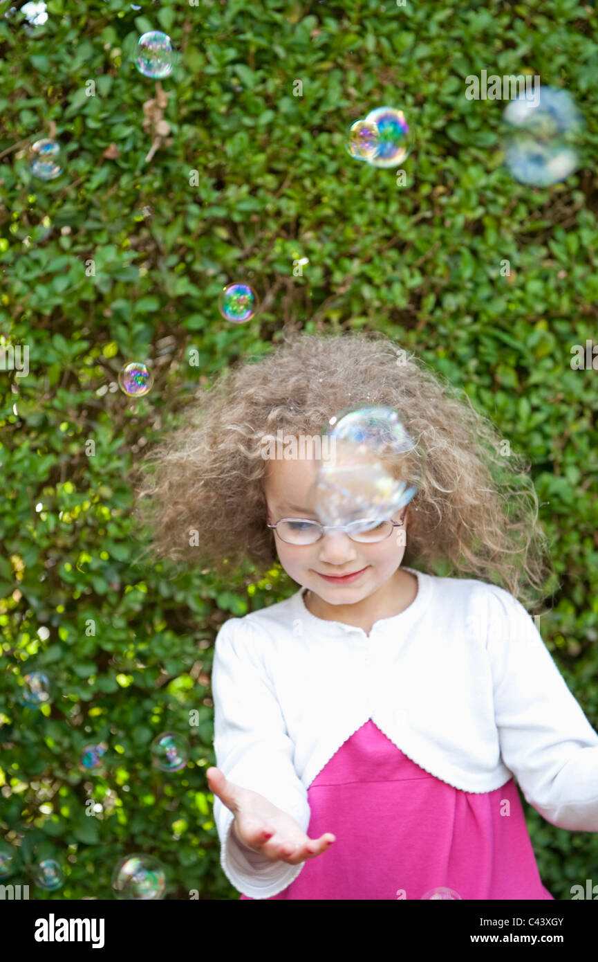 A little girl plays in her garden trying to catch bubbles Stock Photo ...