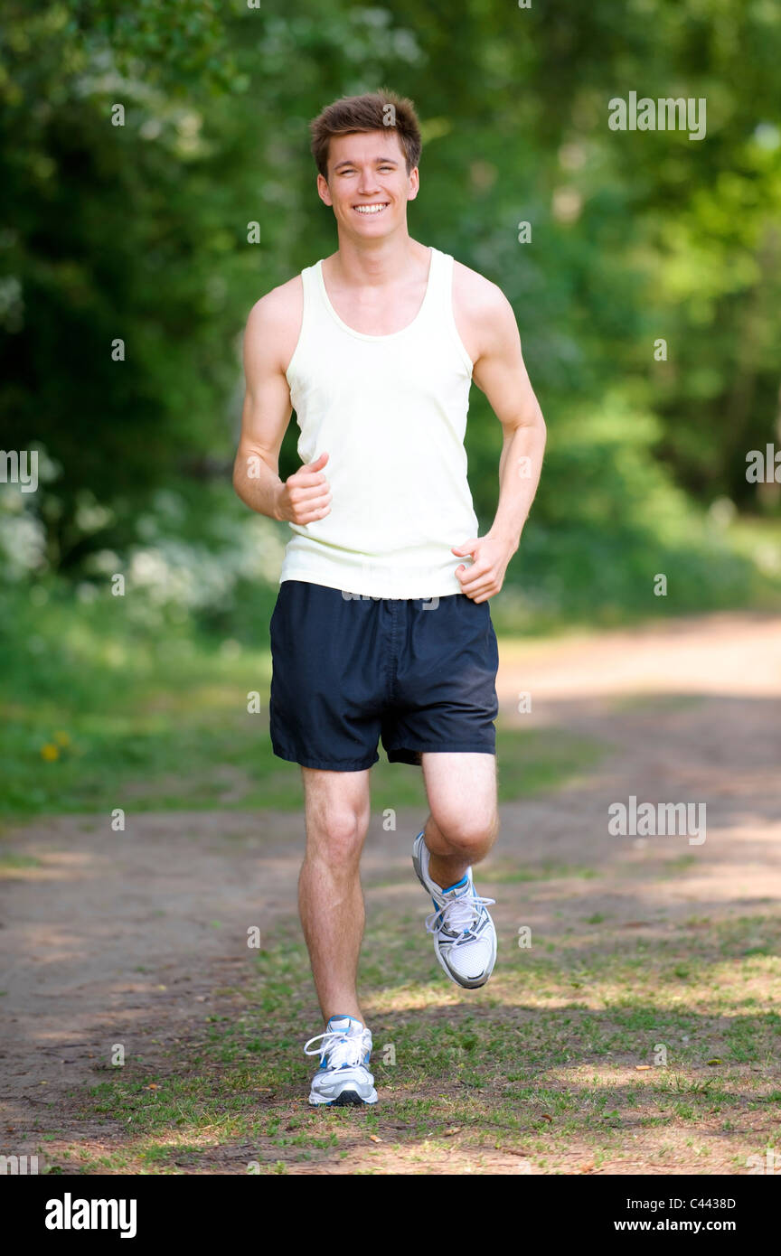 Young and smiling man running in the forest Stock Photo - Alamy