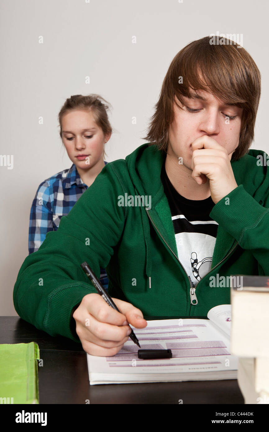 A teenage boy thinking in a classroom, girl in background Stock Photo ...