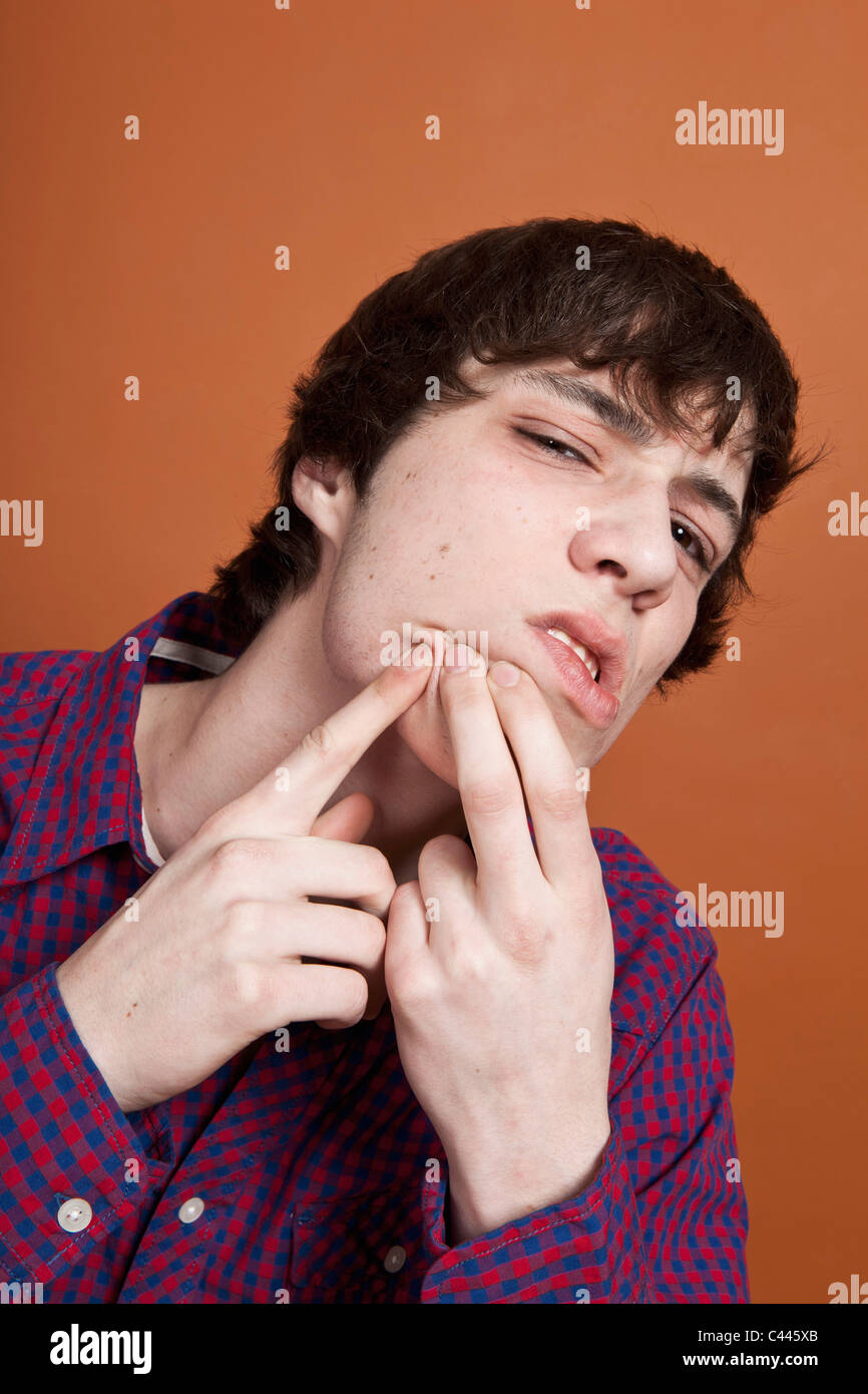 A teenage boy popping a zit on his face, portrait, studio shot Stock ...