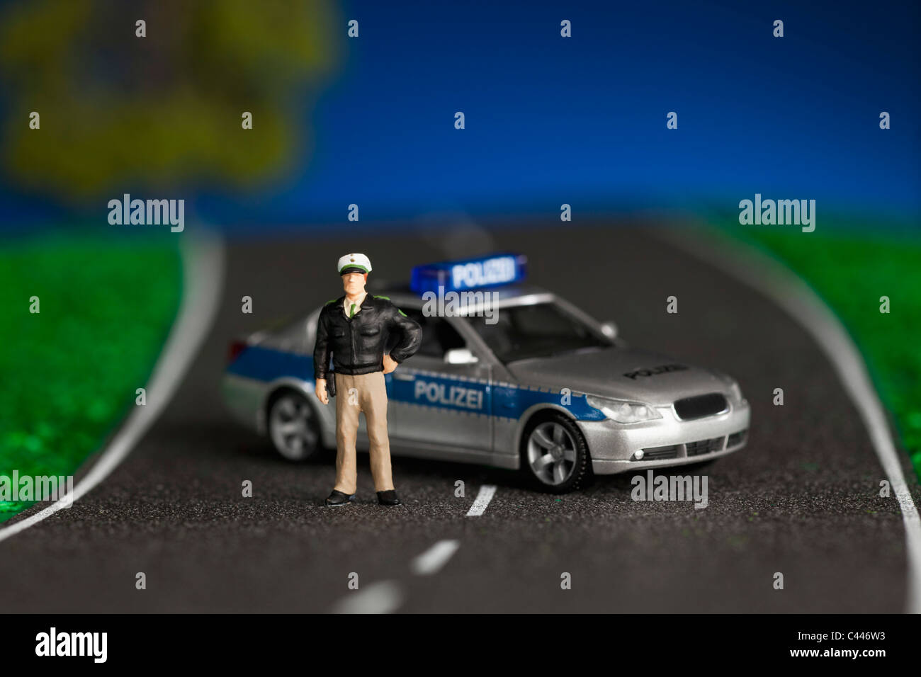 A diorama of a miniature policeman figurine standing by a miniature ...