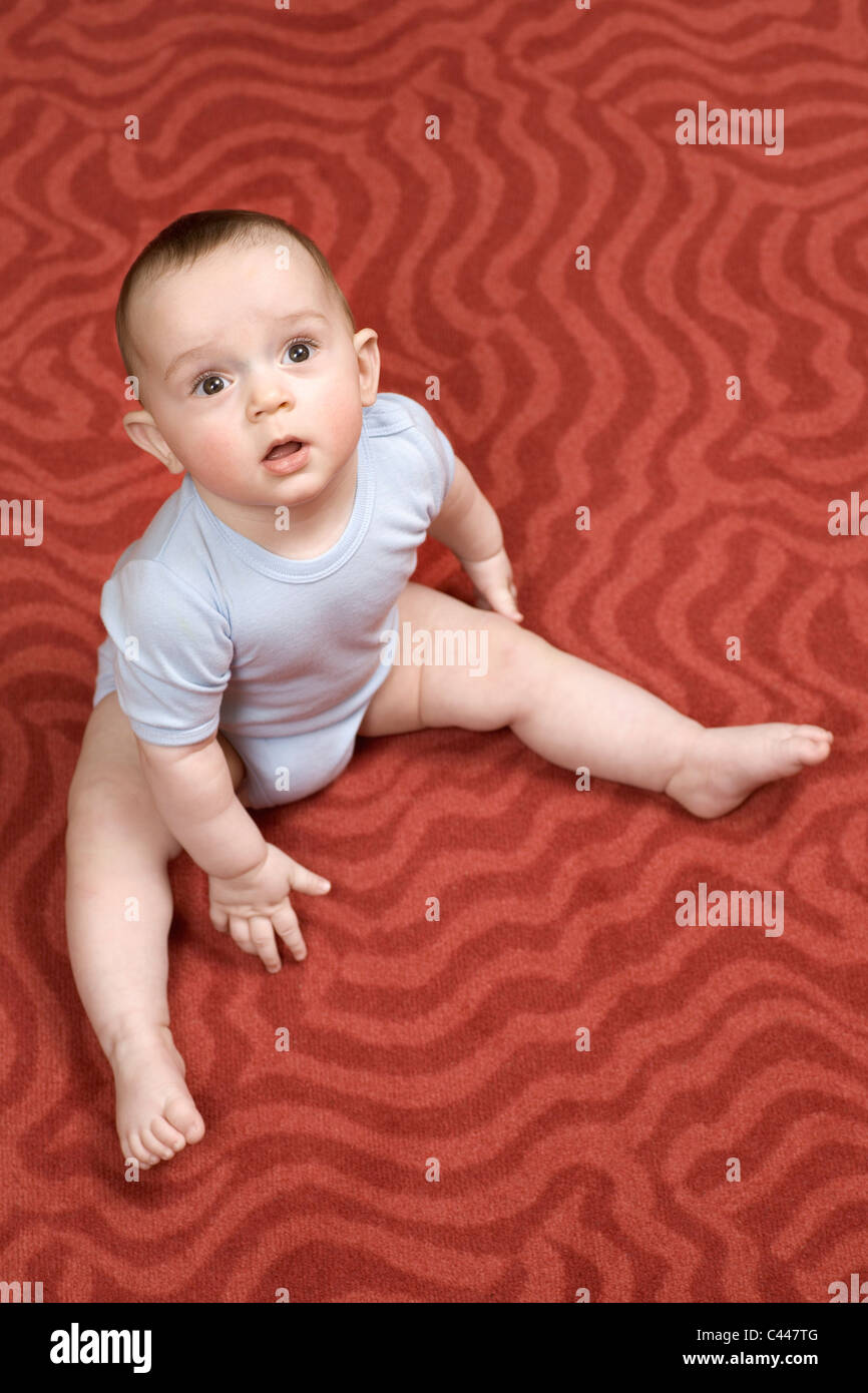 A baby boy sitting on a patterned carpet Stock Photo - Alamy