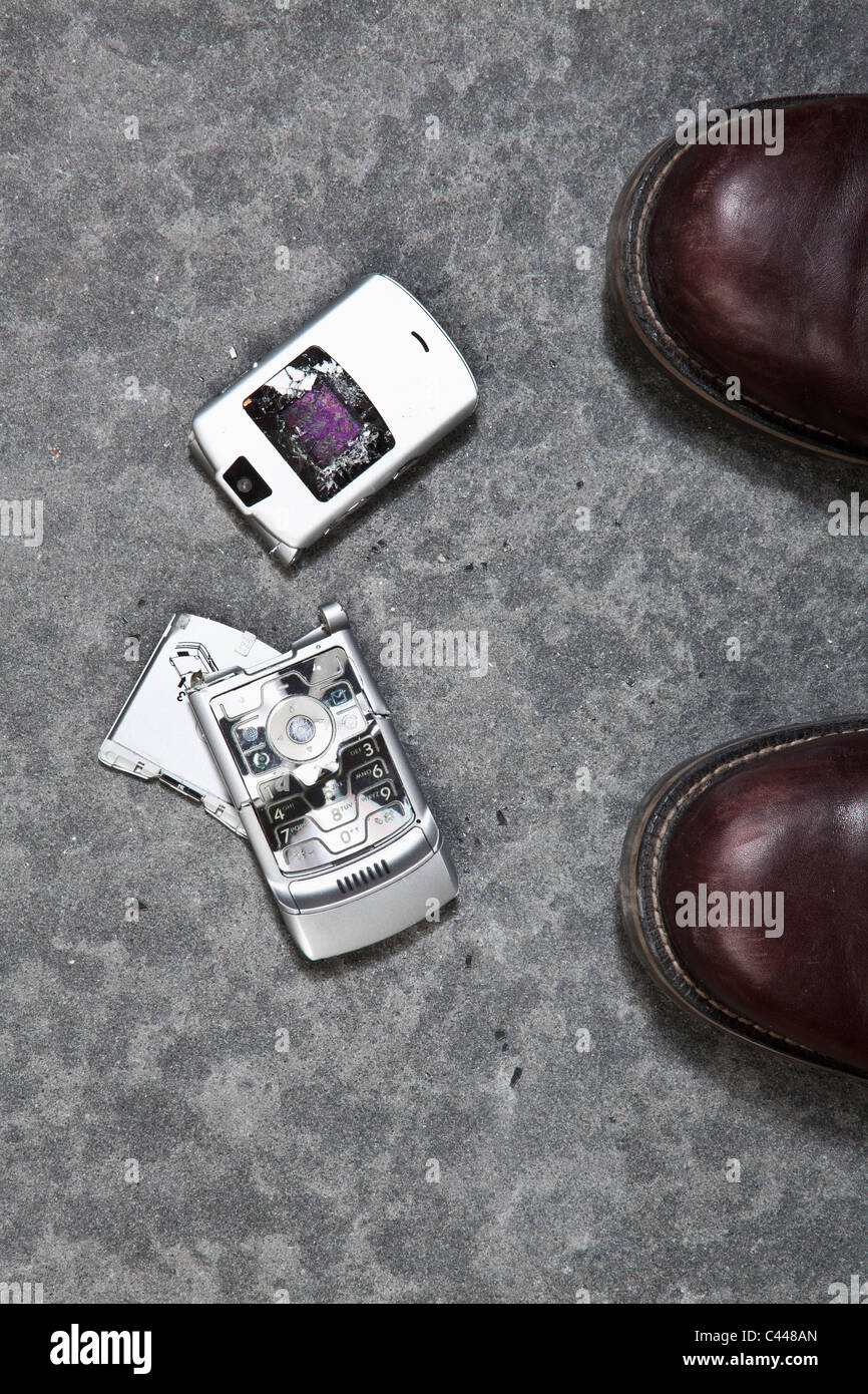 Two booted feet next to a smashed mobile phone Stock Photo - Alamy