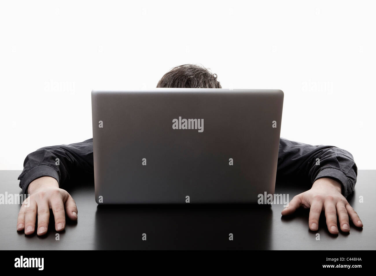 A man hiding behind a laptop Stock Photo - Alamy
