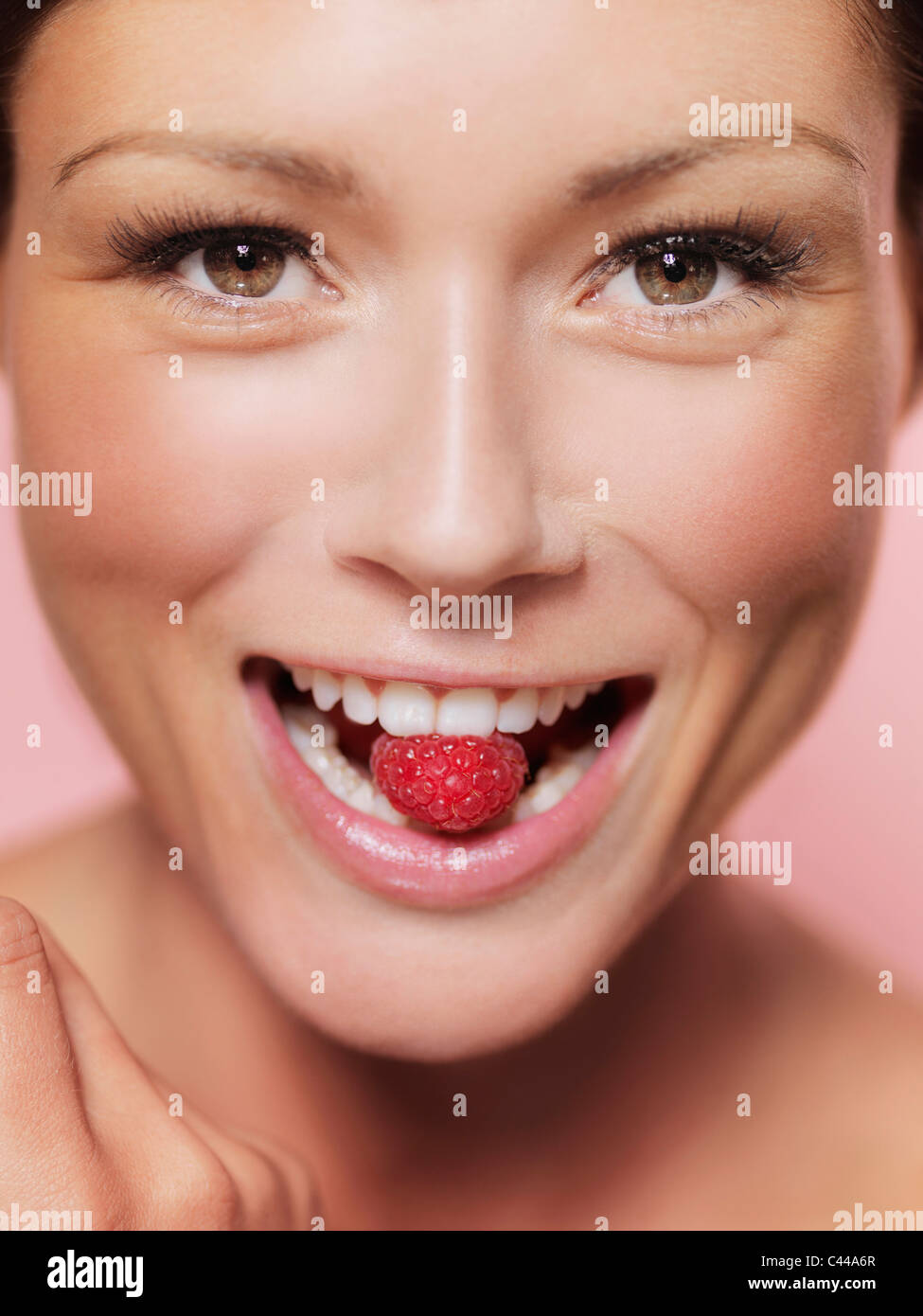 A woman holding a raspberry between her teeth, close-up Stock Photo - Alamy