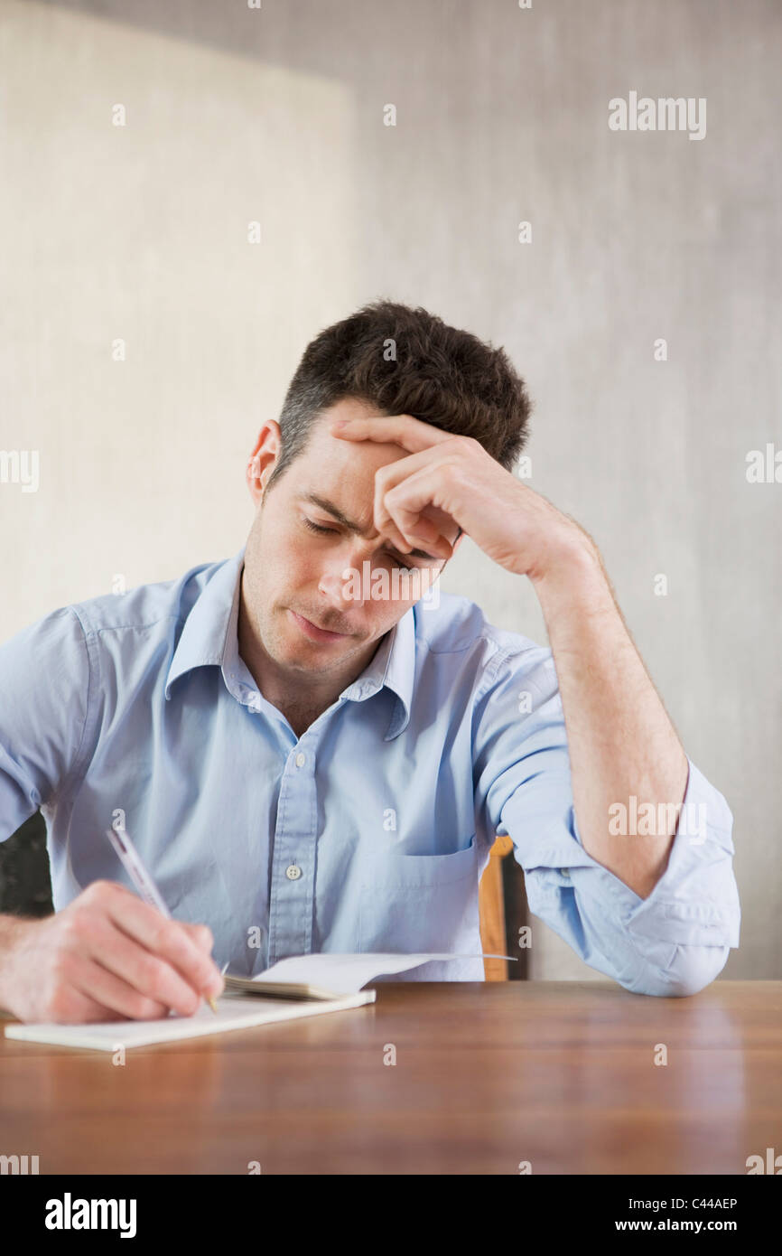 A man frowning while writing a check Stock Photo - Alamy