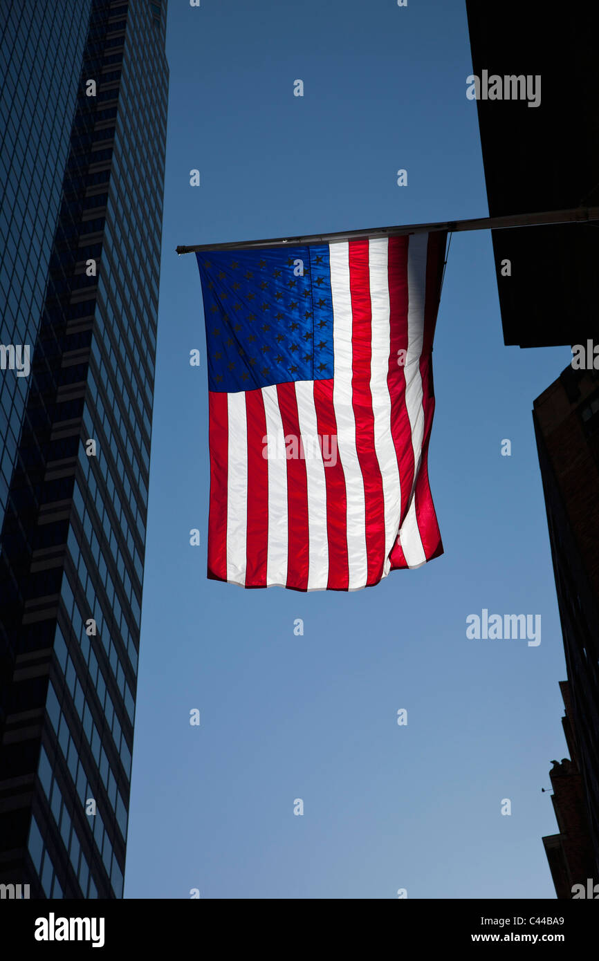 The American flag shown between two tall buildings with a backdrop of a ...