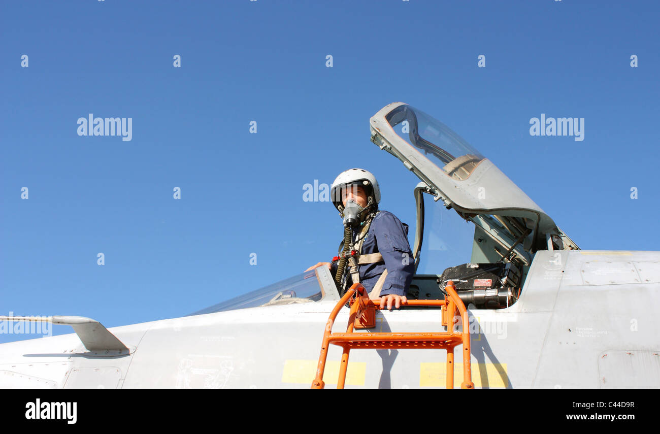 The military pilot in the plane in a helmet in dark blue overalls ...