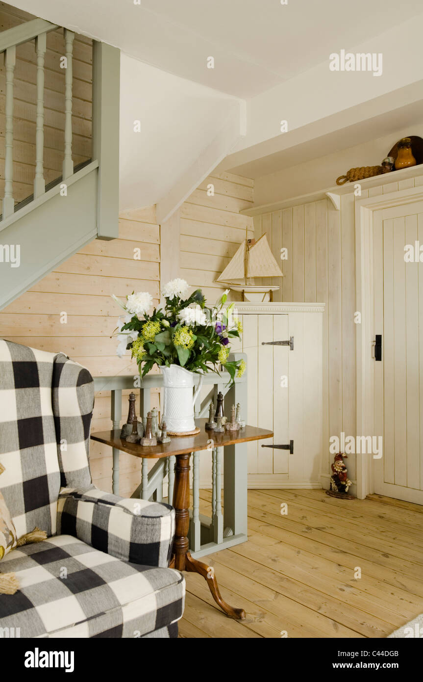 Checked wingback armchair in wood panelled interior with cupboard and ...