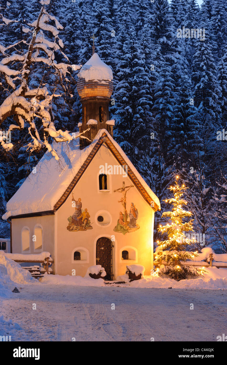 christmas chapel at winter with snow at night and illuminated tree ...