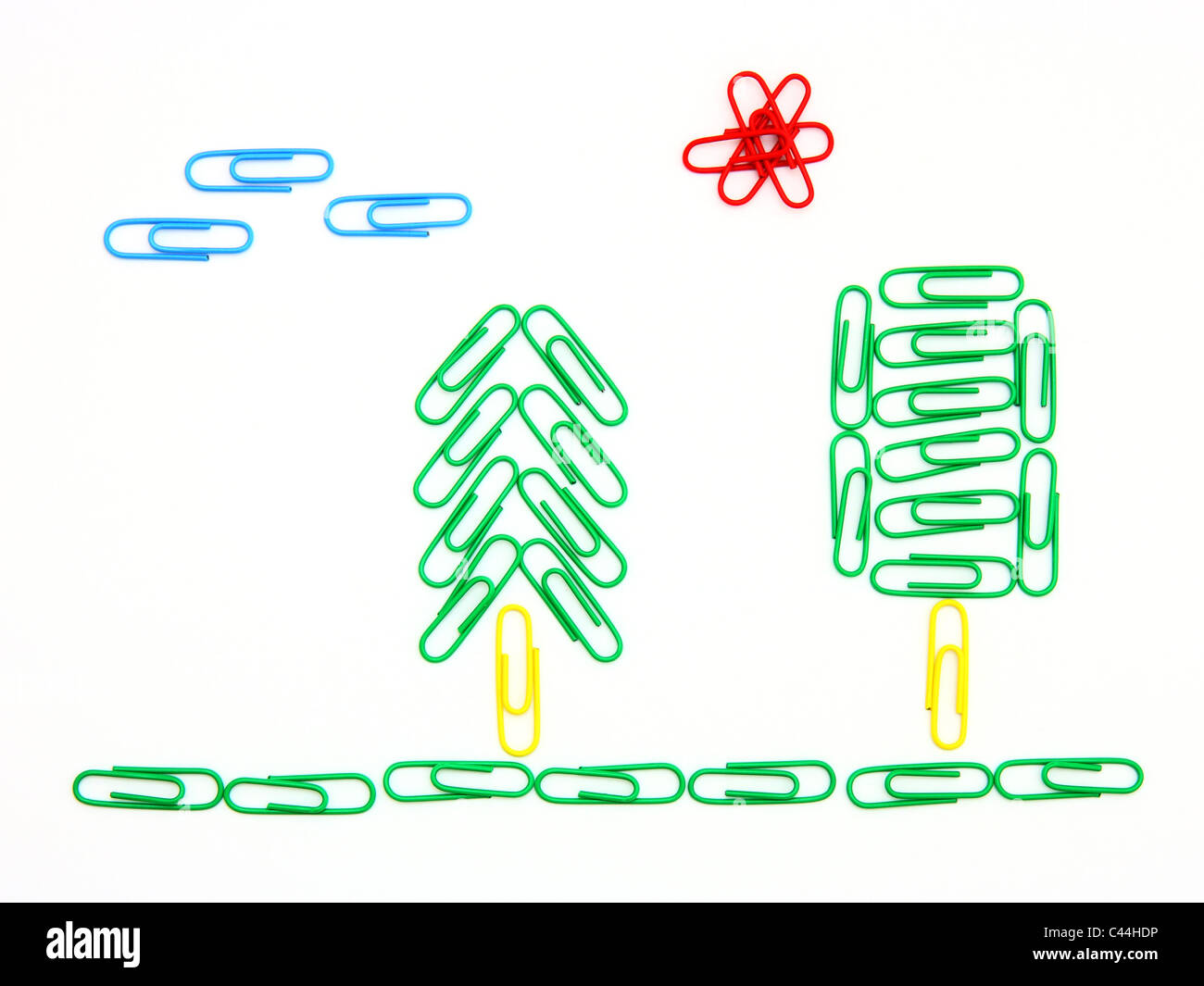 Trees from color paper clips on a white background with clouds and the ...