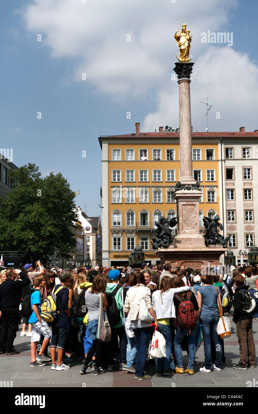 Tourists gather in Marienplatz with the column of St Mary Golden Statue ...