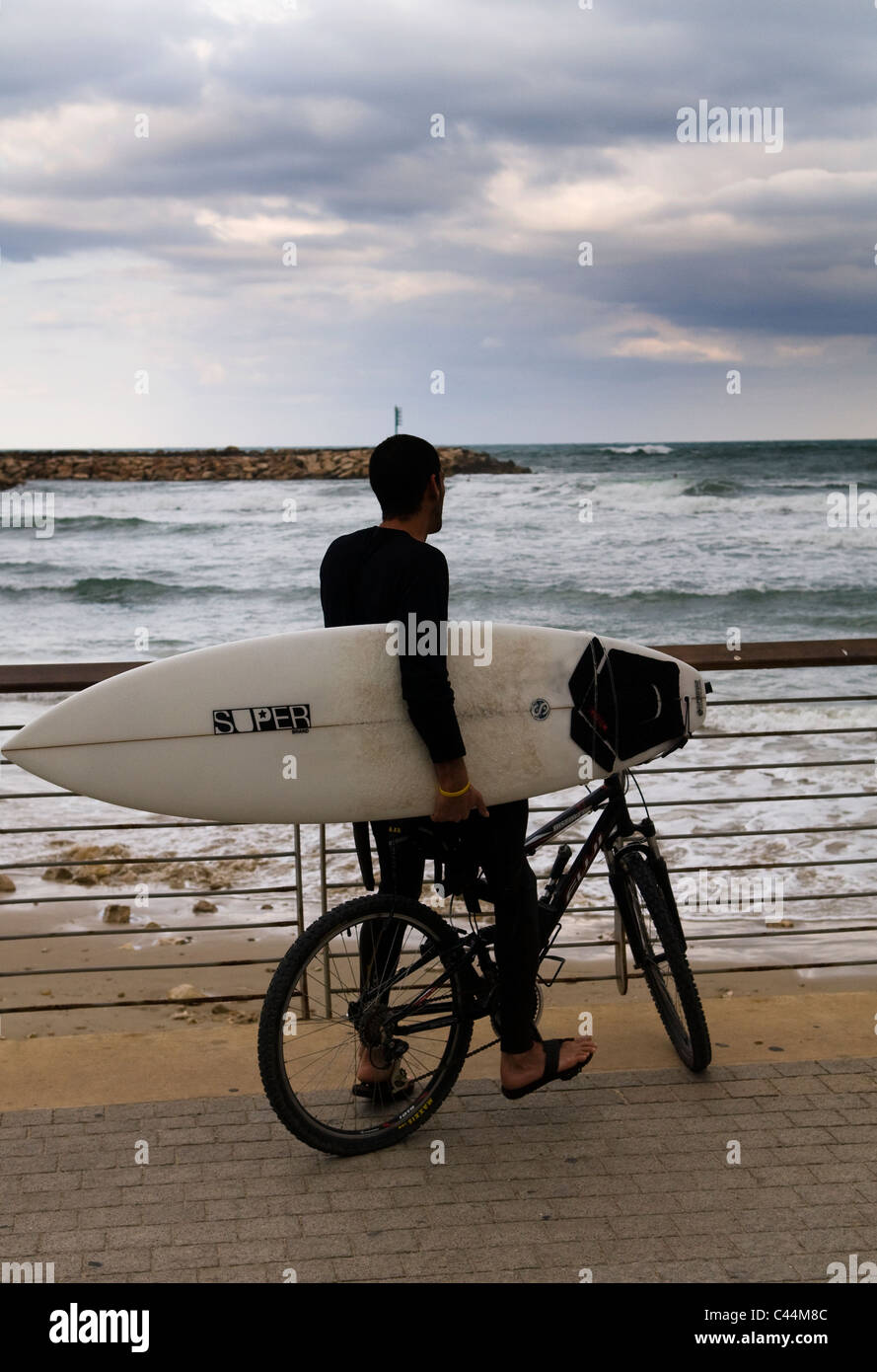 A surfer on his bicycle holding his surfboard Stock Photo - Alamy