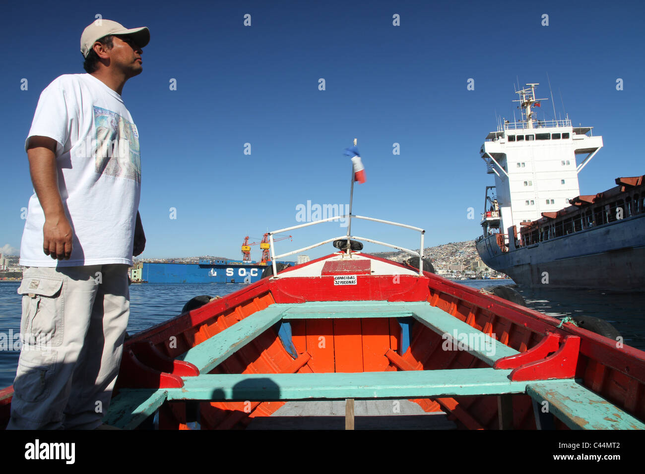 The skipper of a small fishing boat looks at large tanker in the ...