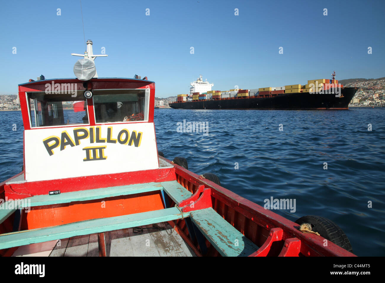 A small fishing boat passes a large freight ship in the harbour at ...