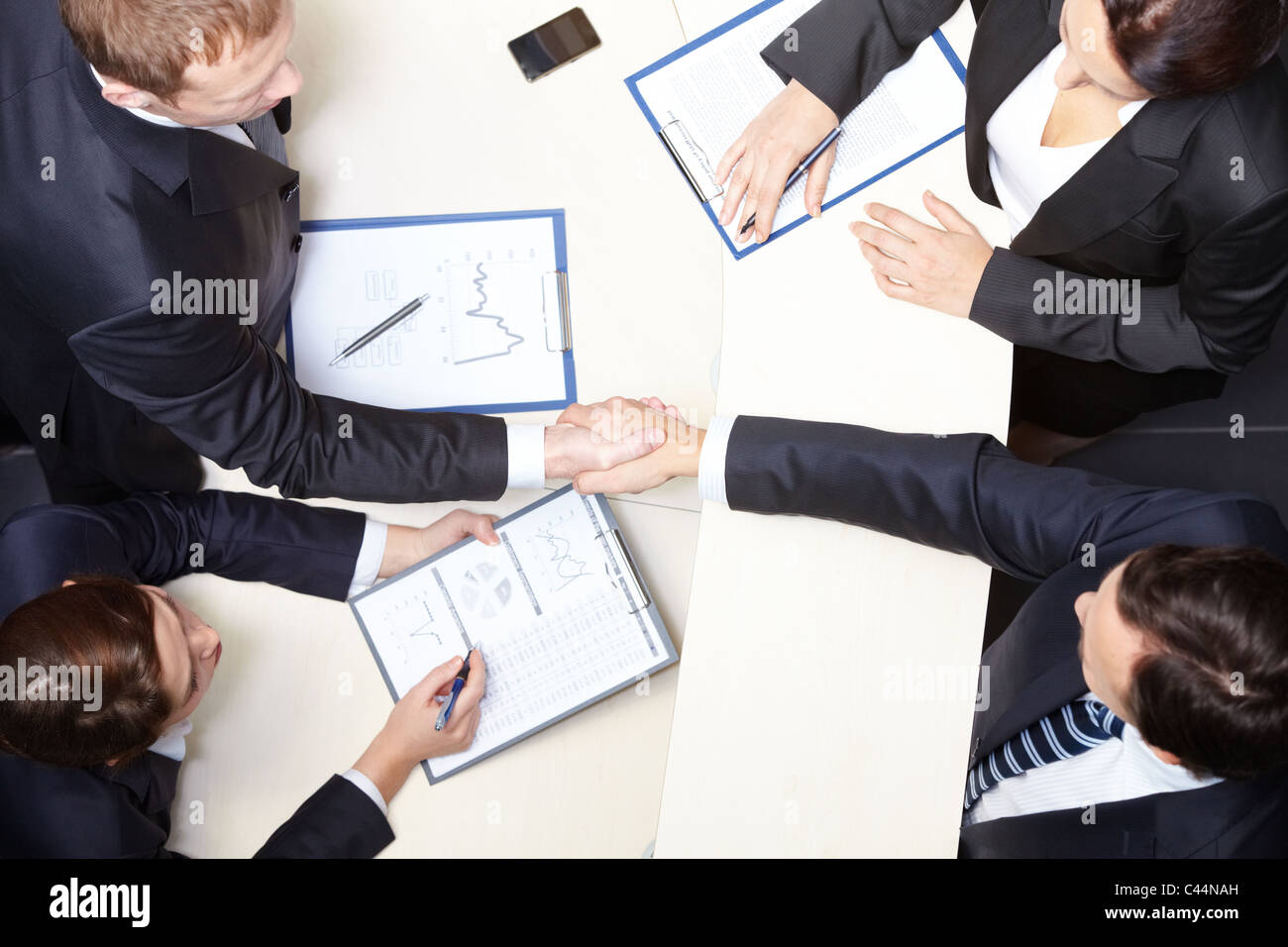 Above view of business partners handshaking after signing contract ...