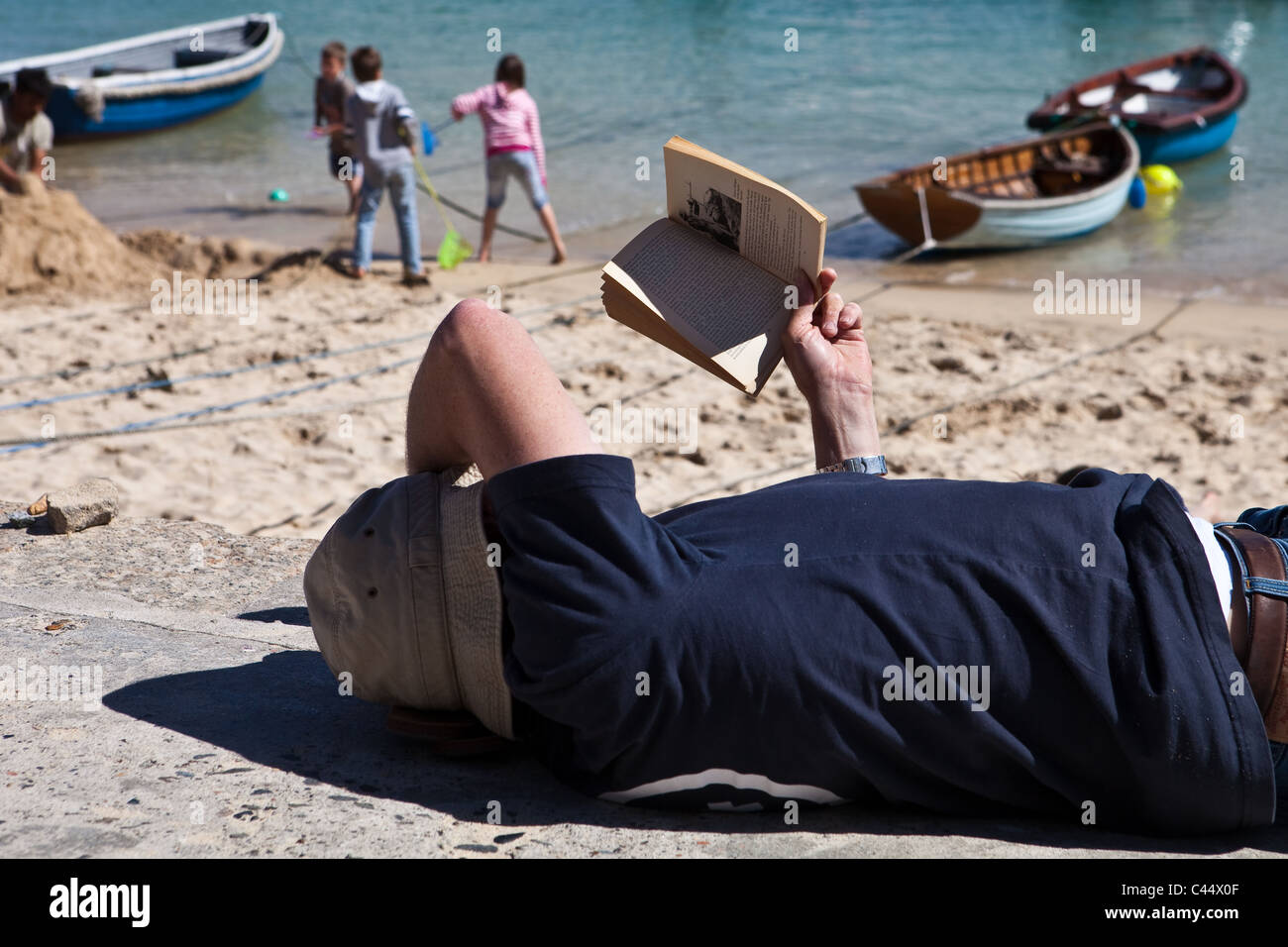 Man reading a book in the sun at the beach in England Stock Photo - Alamy