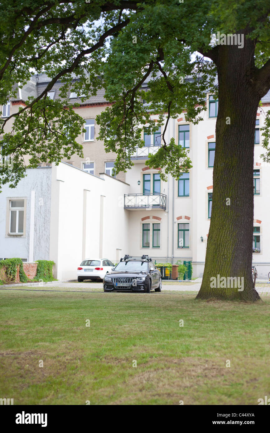Urban tranquility: tree-framed view of residential buildings and parked ...