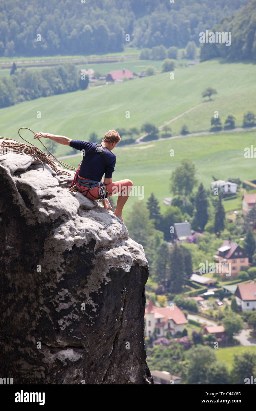 Rock climber sitting at the edge, village seen in distance Stock Photo ...