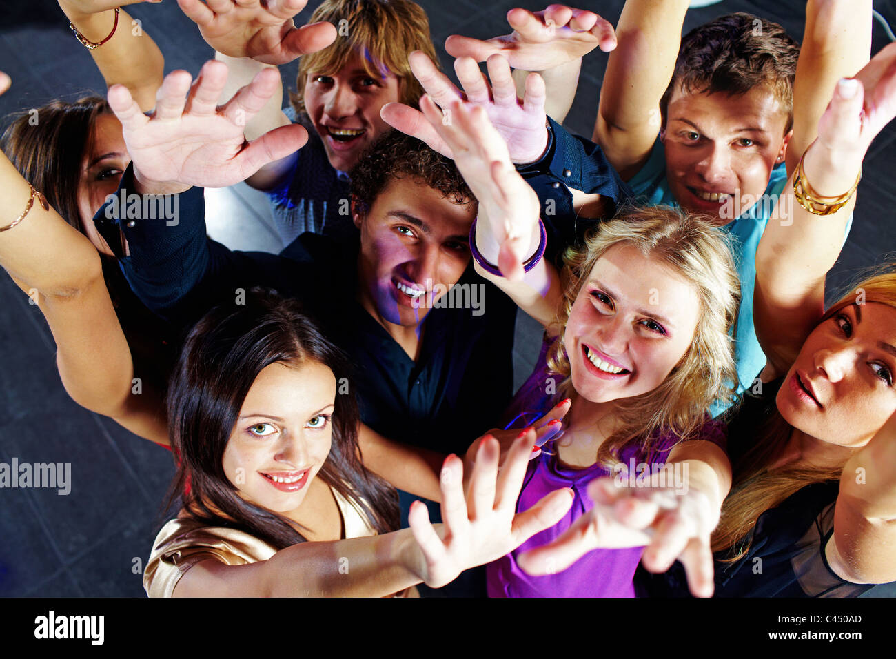Photo of smiling friends raising arms during the party in excitement ...