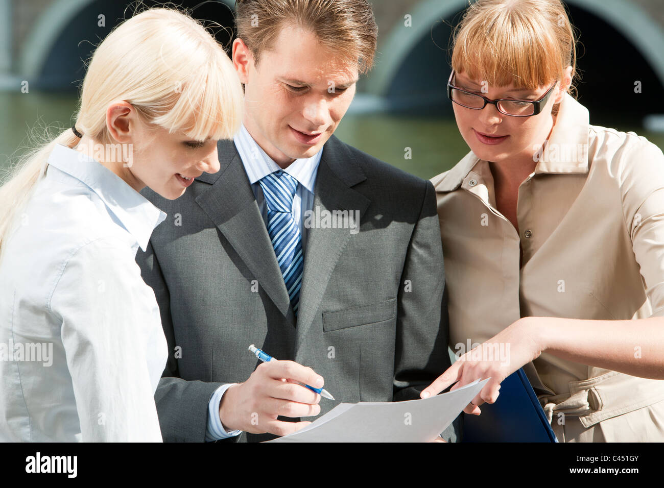 Portrait of friendly business team looking at document in man’s hands ...