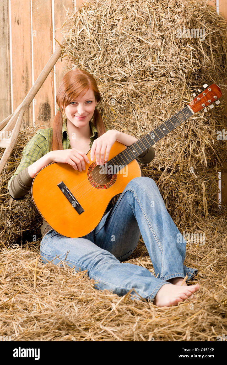Young country woman sitting on hay with guitar in barn Stock Photo - Alamy