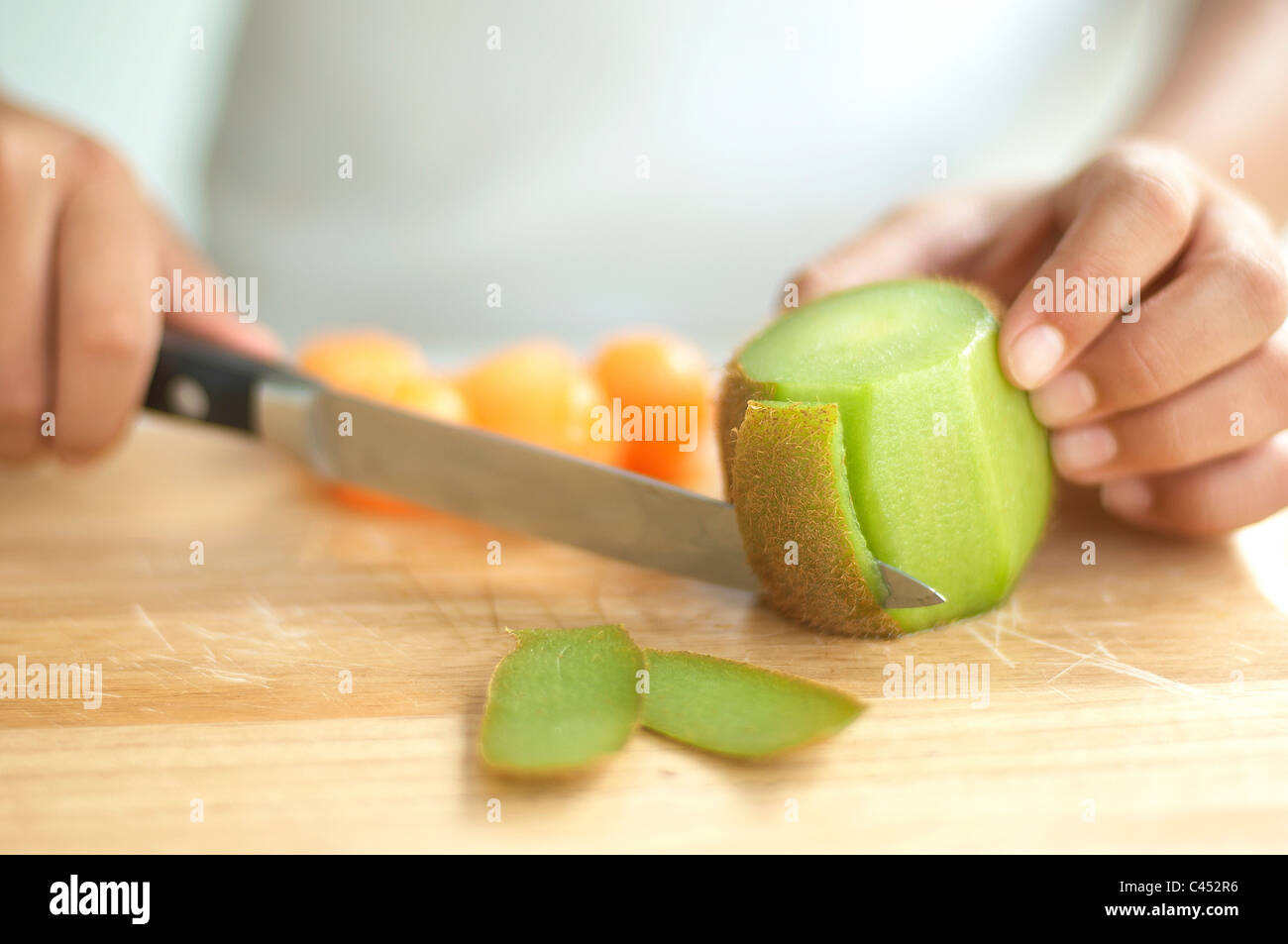 Girl cutting skin off kiwi fruit, close-up Stock Photo - Alamy