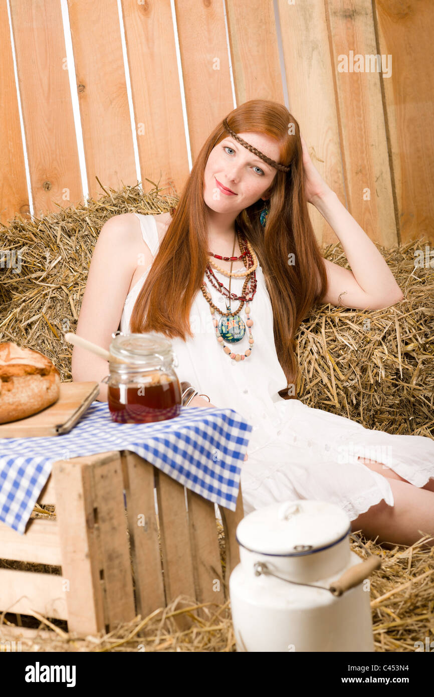 Red-hair young hippie woman breakfast on hay in barn country style ...