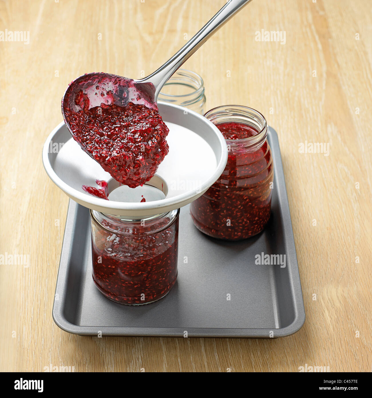 Putting jam into jars through funnel, close-up Stock Photo - Alamy