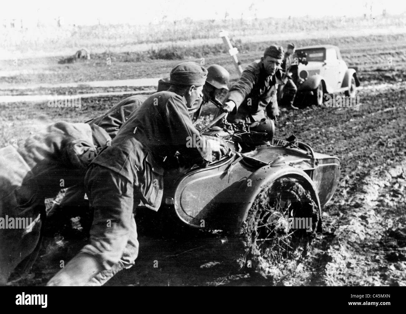 German soldiers push a motorcycle with a sidecar which stranded in the ...