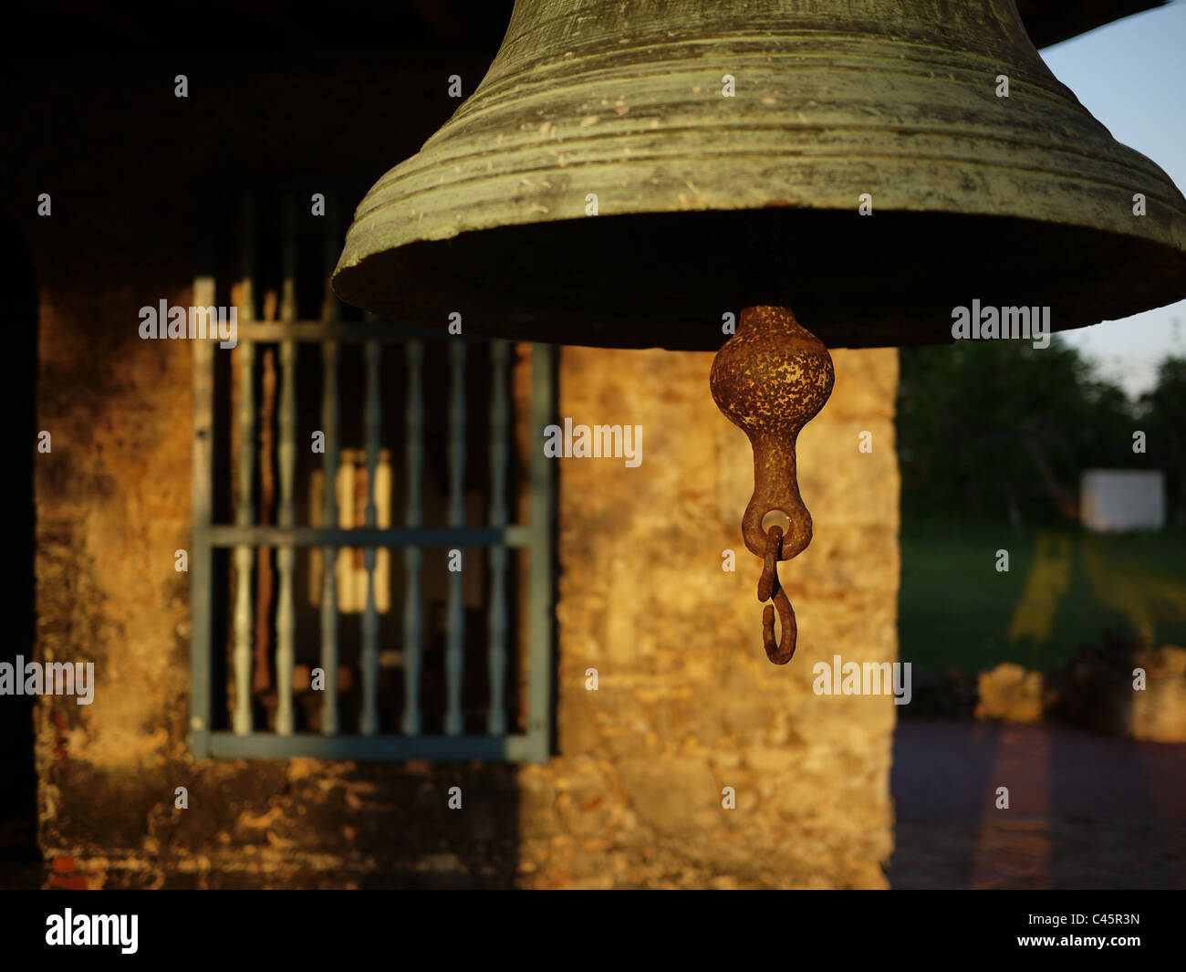An old bell hanging outside an old 18th century building during sunset ...